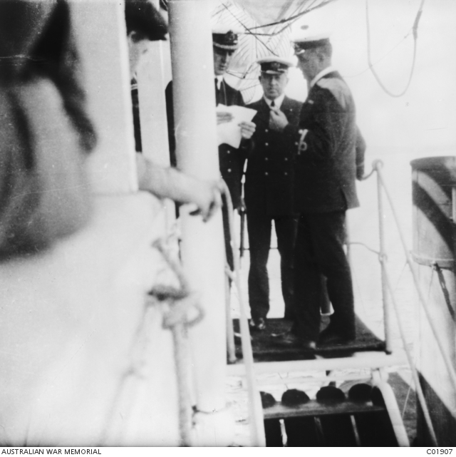 Three naval officers on the troopship HMAT Themistocles receiving ...