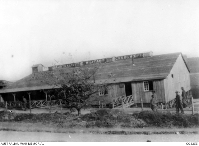 A group of Australian soldiers standing outside a timber building which ...