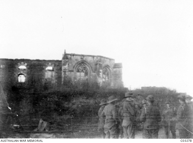 A group of Australian soldiers gathered near the ruins of a church in ...