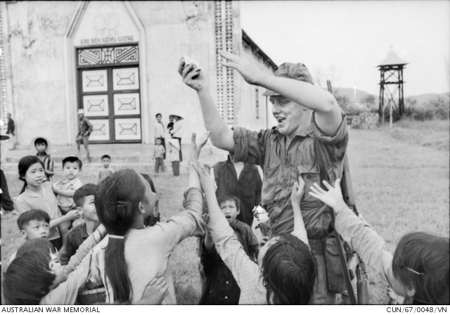 Vietnamese children reach for a small parcel of food being offered by ...