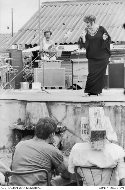 Entertainer Jan Adele sings on stage, accompanied by a guitarist. Two ...