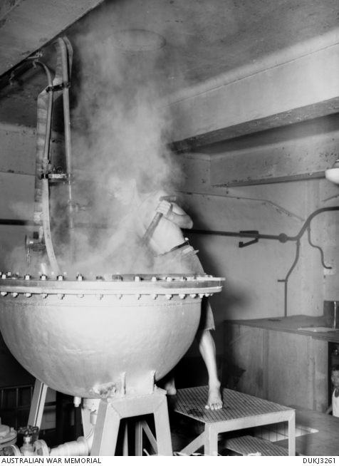A Japanese man works at stirring a large vat of hot liquid, probably a ...