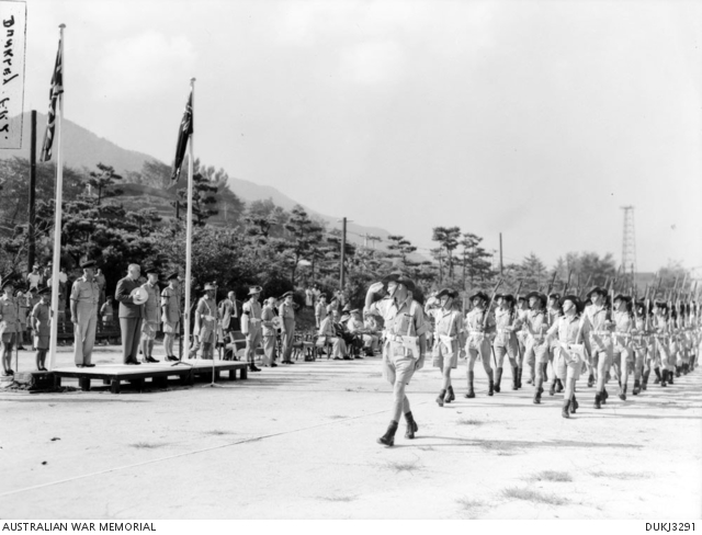 Standing on a dais, an official party which includes the Prime Minister ...