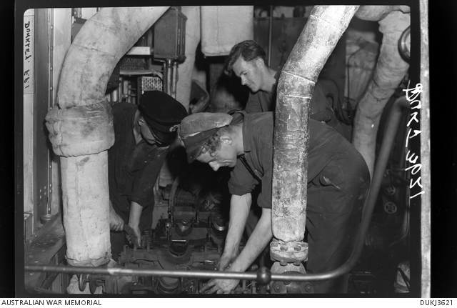 Three unidentified crew members of the RAN destroyer HMAS Bataan, carry ...