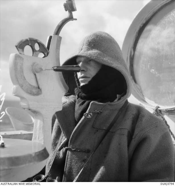 An unidentified crew member of the RAN destroyer HMAS Bataan, rugged up ...