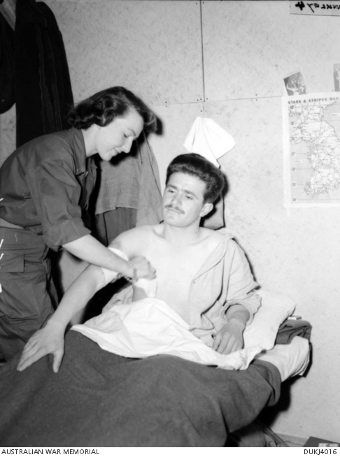 An unidentified US Army nurse bandaging the arm of an injured soldier ...