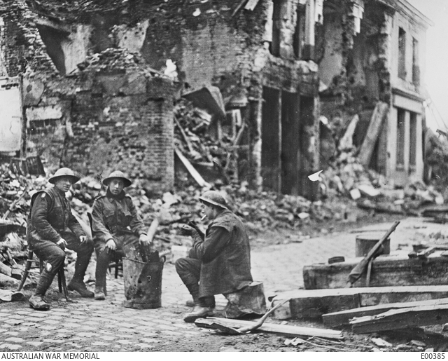 Three soldiers warming themselves over a stove, made from a battered ...