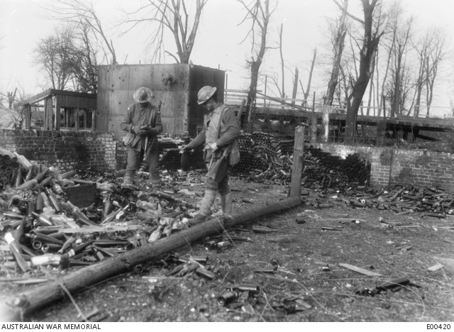 Two members of the 22nd Battalion check out the stacks of empty wine ...
