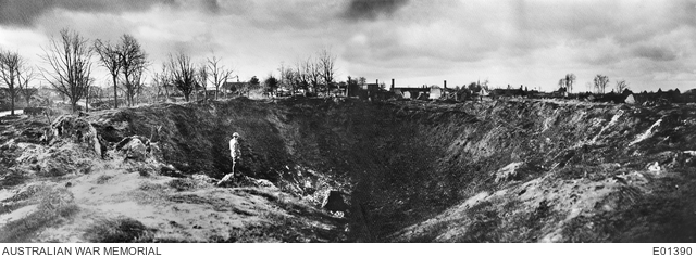 An unidentified soldier viewing a huge crater caused by a mine which ...