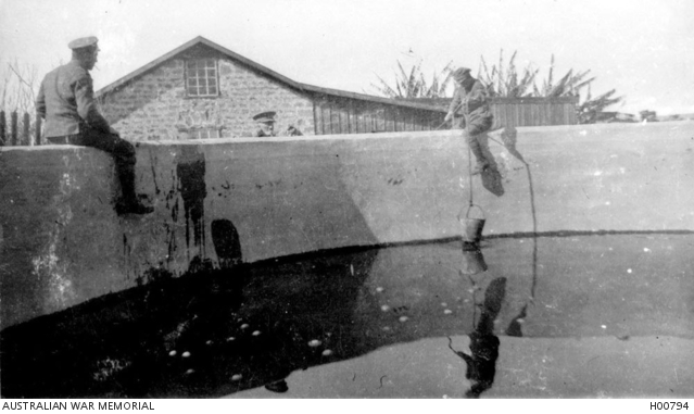 Two soldiers lower their buckets, dipping for mosquito larvae in a ...