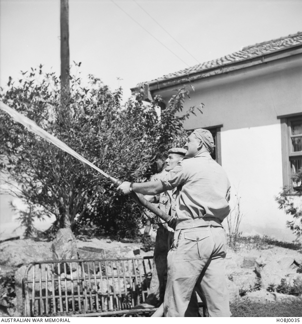Unidentified soldiers directing water onto the smouldering roof of a ...