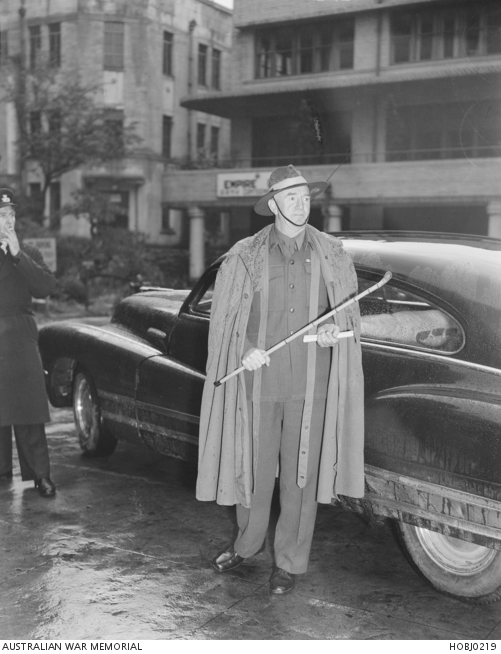 Warrant Officer Class 2 (WO2) Frank Fisher, wearing a raincoat, arrives ...