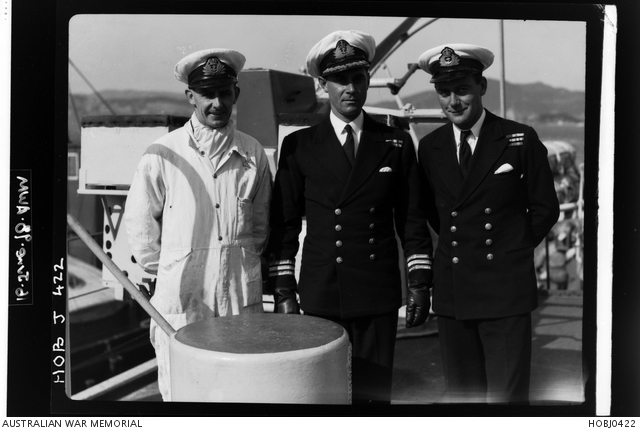 An RAN Commander (Cdr) (centre), probably V G Jerram, stands on the ...