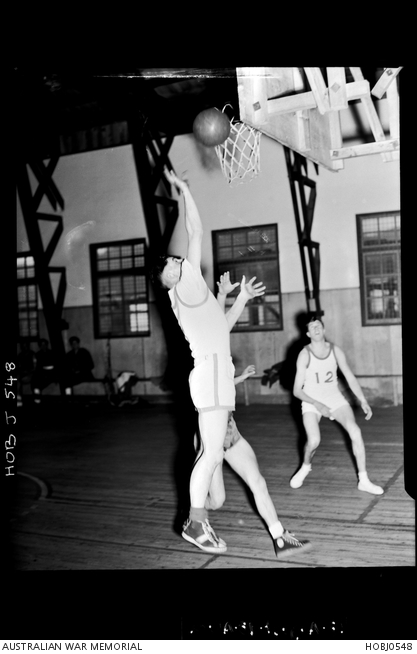 An unidentified basketball player, in a white singlet, shoots for goal ...