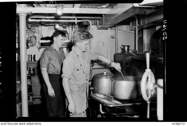 Two crew members on the frigate HMAS Shoalhaven, cook up a meal in some ...