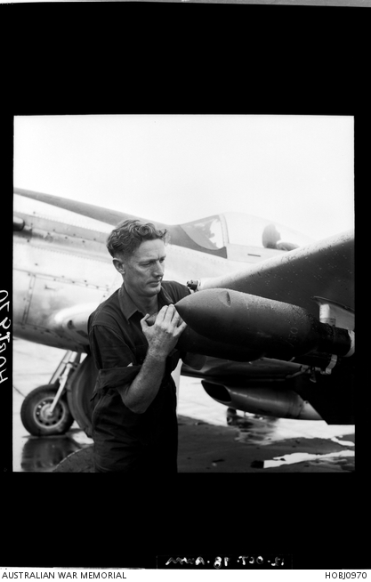 An unidentified RAAF armourer from 77 Squadron RAAF, adjusts rocket ...