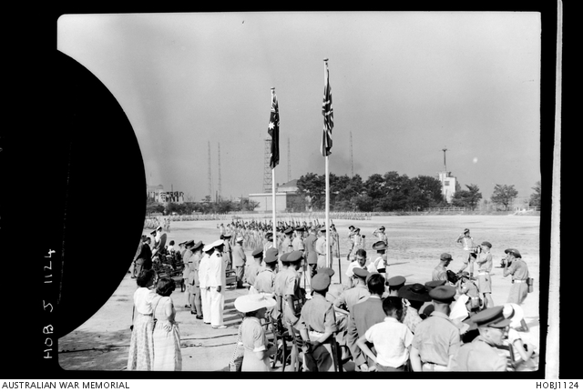 Standing on a dais, an official party which includes the Prime Minister ...