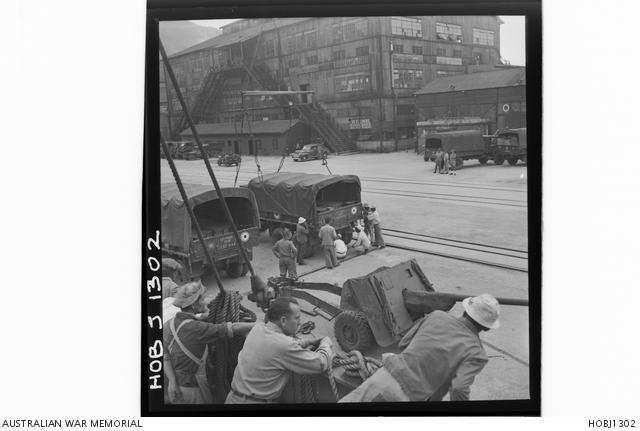 A group of Japanese labourers prepare to load military trucks onto the ...
