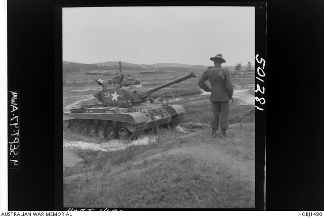 A US M26 Pershing tank makes its way down a Korean road, while a ...