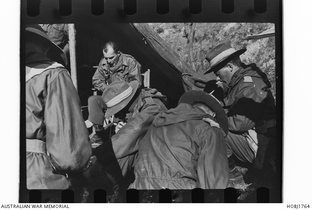 Lieutenant Colonel (Lt Col) I B Ferguson sits at the front of his tent ...