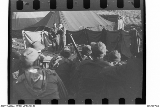 Larry Adler (right) performs for troops on an impromptu stage in a camp ...