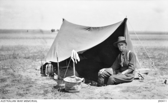 Reverend William Fraser sitting outside his tent, whilst in camp with ...