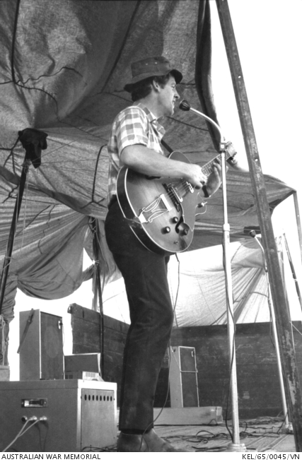 Ian Turpie playing his guitar on a makeshift stage at an airbase north ...