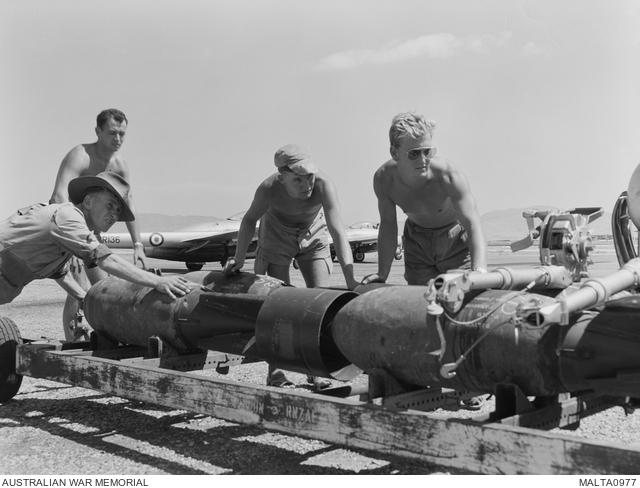 Four armourers push a trolley of 500 pound bombs that they are about to ...