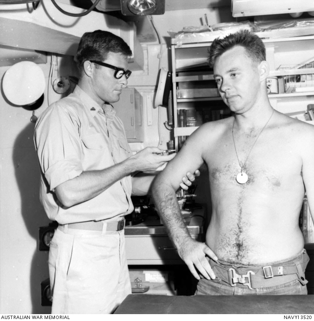 Surgeon Lieutenant Leo Barnett inoculates Leading Seaman Darel Beswick ...