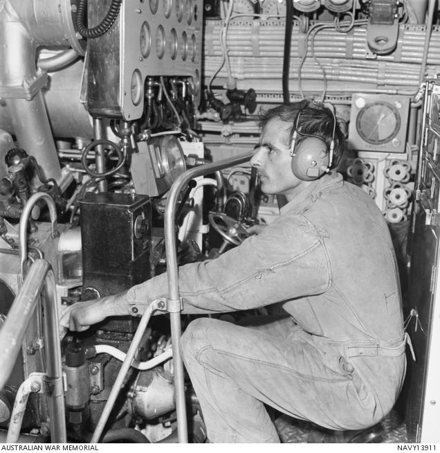 An unidentified crew member makes adjustments to an engine and checks ...