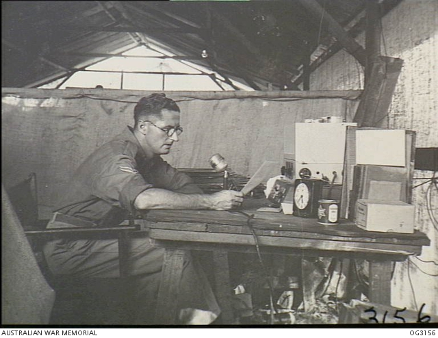 LABUAN, NORTH BORNEO. A RAAF CORPORAL AT THE MICROPHONE ANNOUNCING THE ...