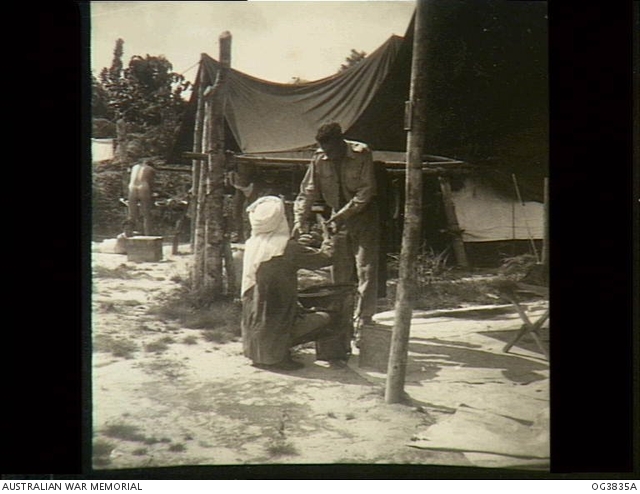 LABUAN, NORTH BORNWO. C. 1946-03. IN THE RAAF CAMPSITE SHOWING A MEMBER ...