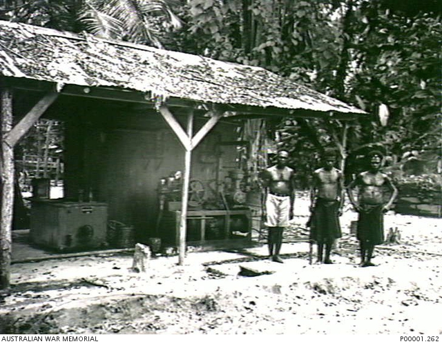 THE SOLOMON ISLANDS, 1945-10-12. THREE NATIVES OUTSIDE A FORMER ...