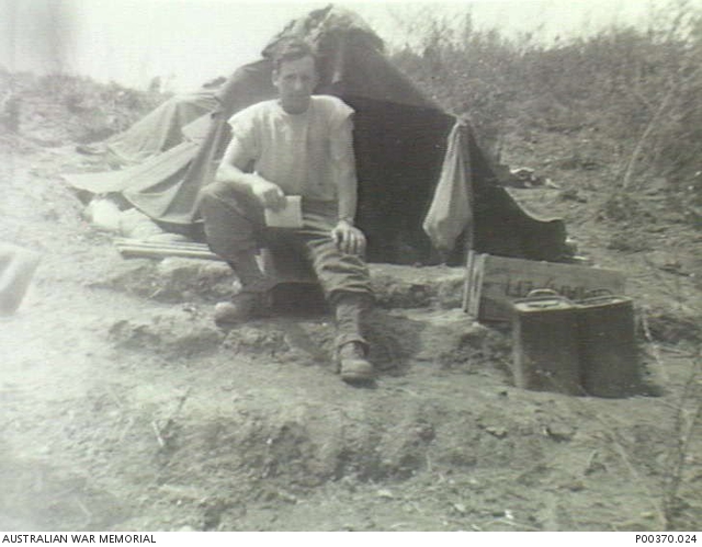 'PADDY' GRACE IN FRONT OF HIS TENT. THE SQUARE CANS ARE 18 MM MORTAR ...