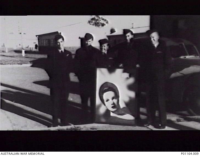 WAGGA WAGGA, NSW. 1942. MEMBERS OF NO. 31 SQUADRON RAAF HOLDING A PINUP ...