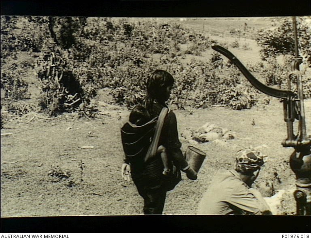 Probably Kham Duc, Vietnam. 1965. A young Montagnard woman waits with a can in her hand at a ...