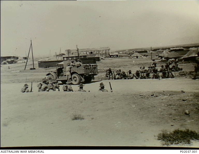 Members of 2/2nd Battalion wait beside a road and a jeep near their ...