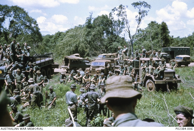 A large crowd of Australian soldiers gathers on and among army trucks ...