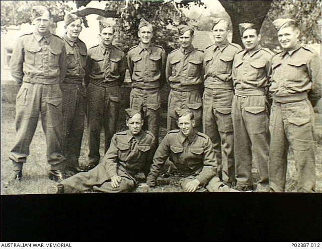Outdoors group portrait of Australian prisoners of war (POWs), most of ...