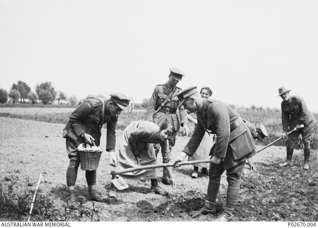 Officers of the 4th Australian Machine Gun Company helping two women ...