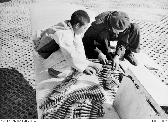 Heads down, an armament fitter arms a 77 Squadron RAAF P-51D Mustang as ...