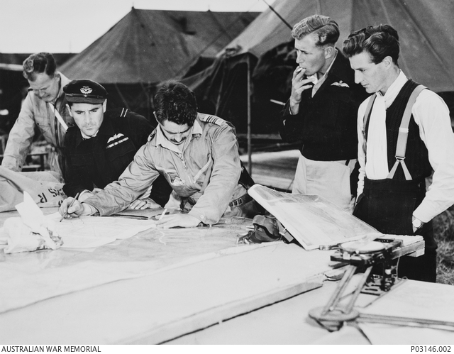 Mustang pilots of No. 77 (Fighter) Squadron RAAF study a target map at ...