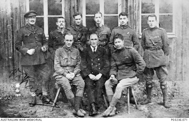 Outdoor portrait of nine Prisoners of War (POW). Identified seated on ...