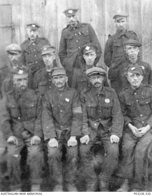 Outdoor portrait of a group of unidentified Prisoners of War (POW) at ...