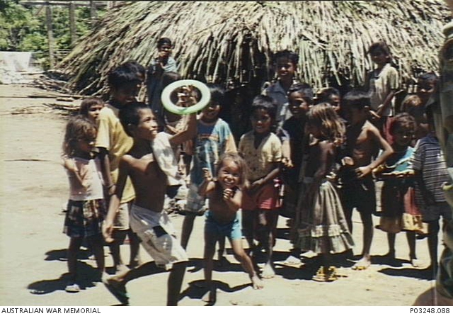 Timorese children playing with a green frisbee given to them by a ...
