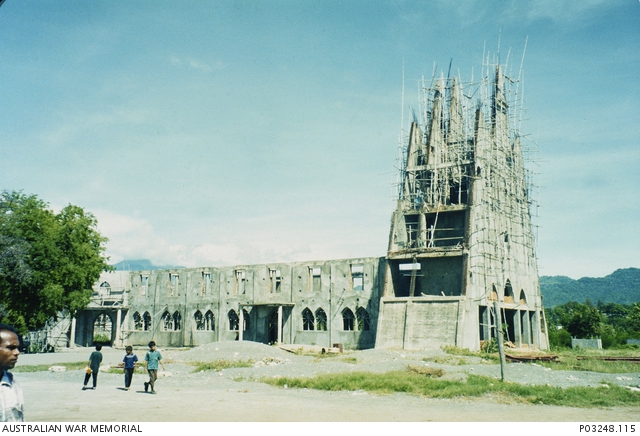 Timorese children walking past the partially constructed Suai Cathedral ...