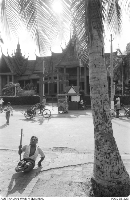 Using a wooden pole to assist him, a polio victim slides his way across ...