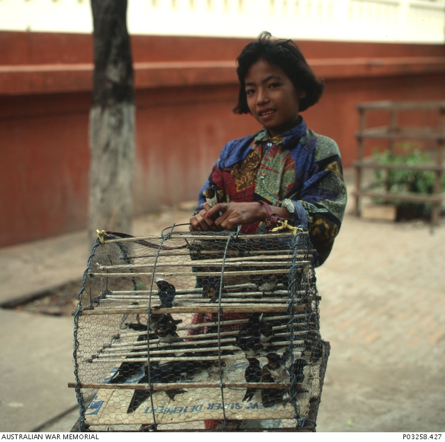 A young girl sells birds from a makeshift cage at the base of the Wat ...