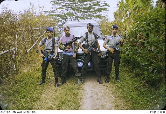 Indonesian Police, armed with machine guns, standing in front of a ...