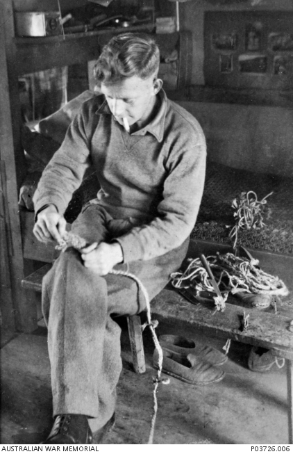 An unidentified prisoner of war (POW), sitting on the side of a wooden ...